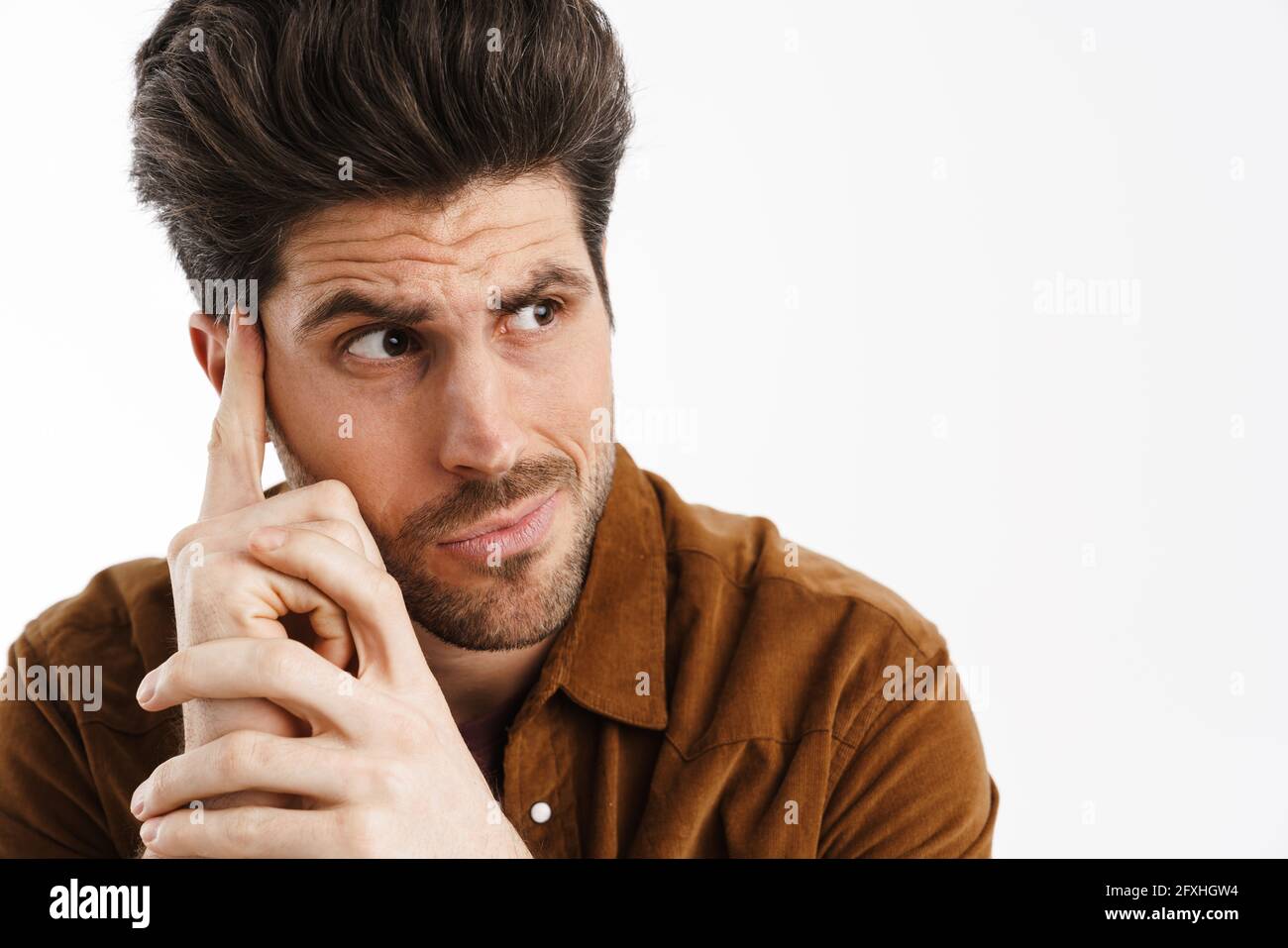 Brooding young unshaven man posing and looking aside isolated over ...