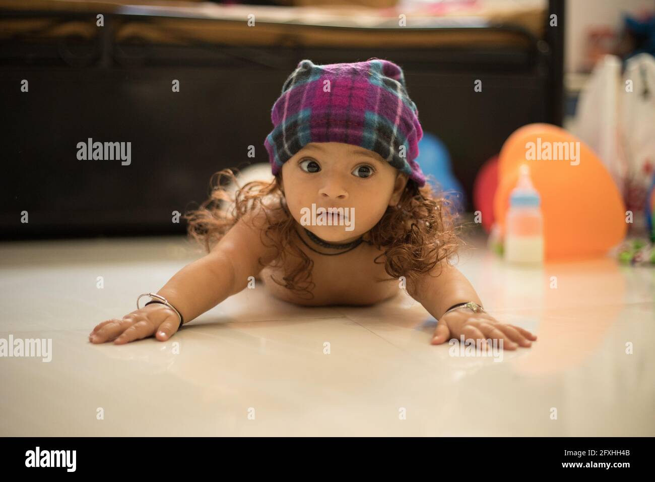 Cute Indian baby girl in a diaper crawling on the floor in Mumbai ...
