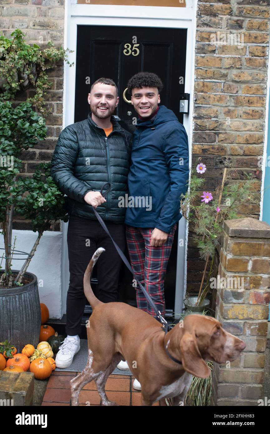 Portrait happy gay male couple with dog on front stoop Stock Photo - Alamy