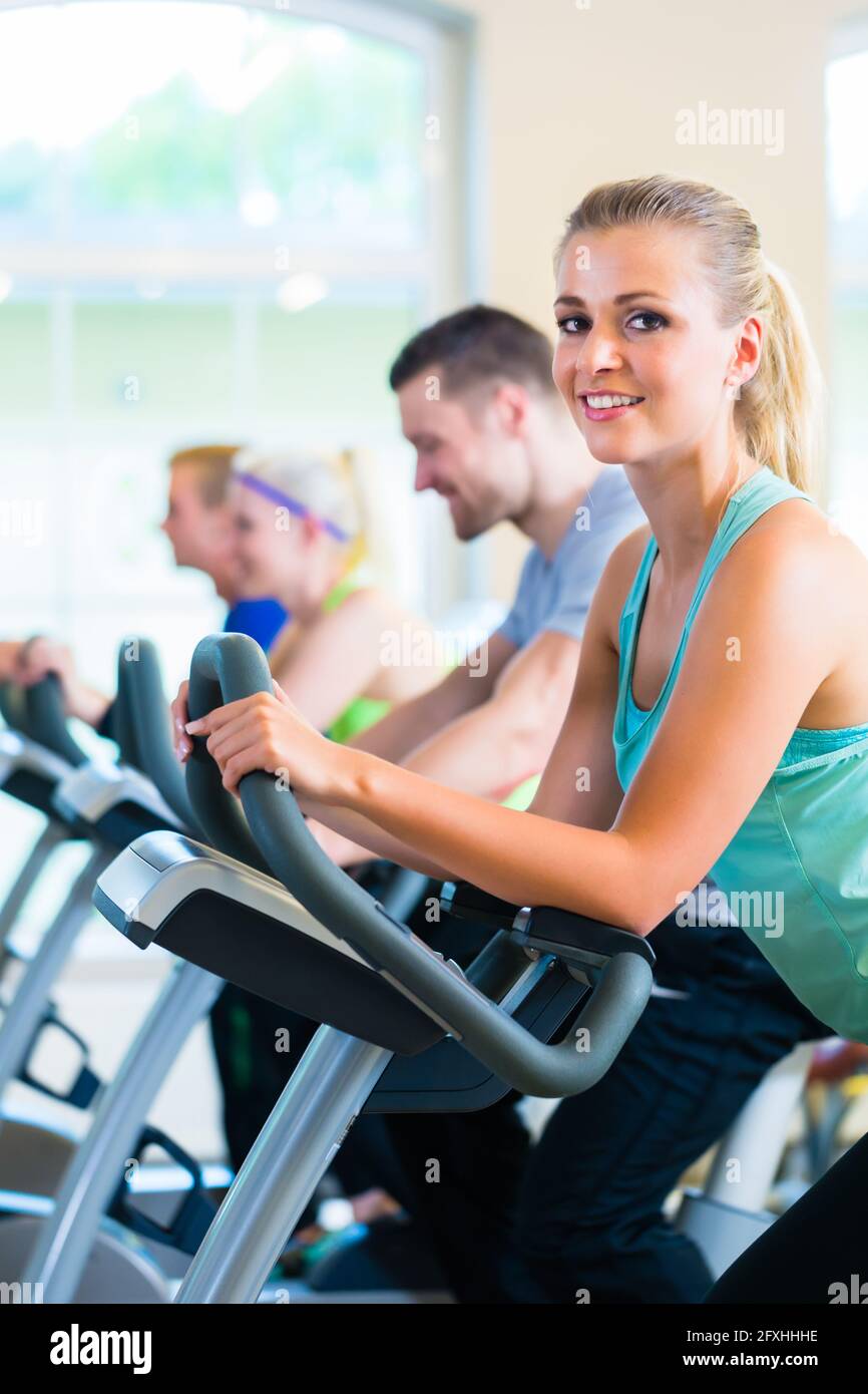 Group of fitness people in sport gym spinning on bicycles Stock Photo ...