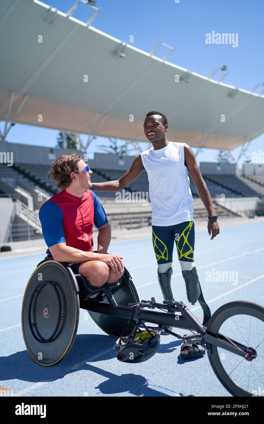 Happy male amputee and paraplegic athlete on sunny sports track Stock ...