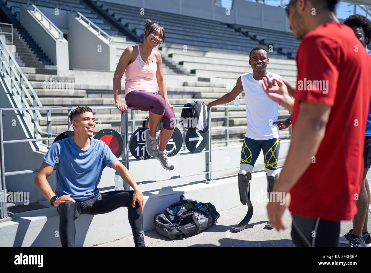 Young athlete friends talking in sunny sports stadium Stock Photo - Alamy