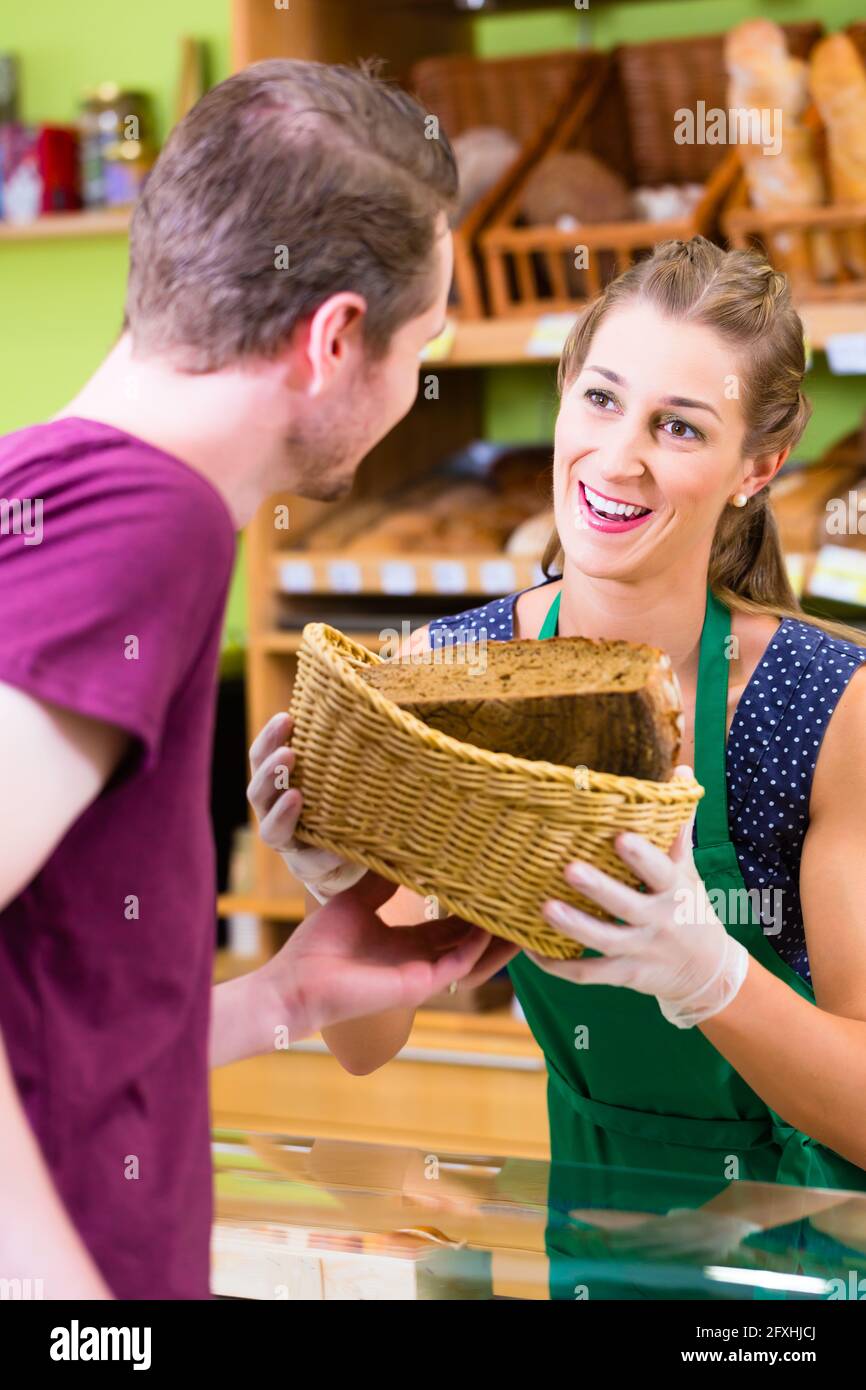 Female baker at organic supermarket bakery offering costumer bread ...