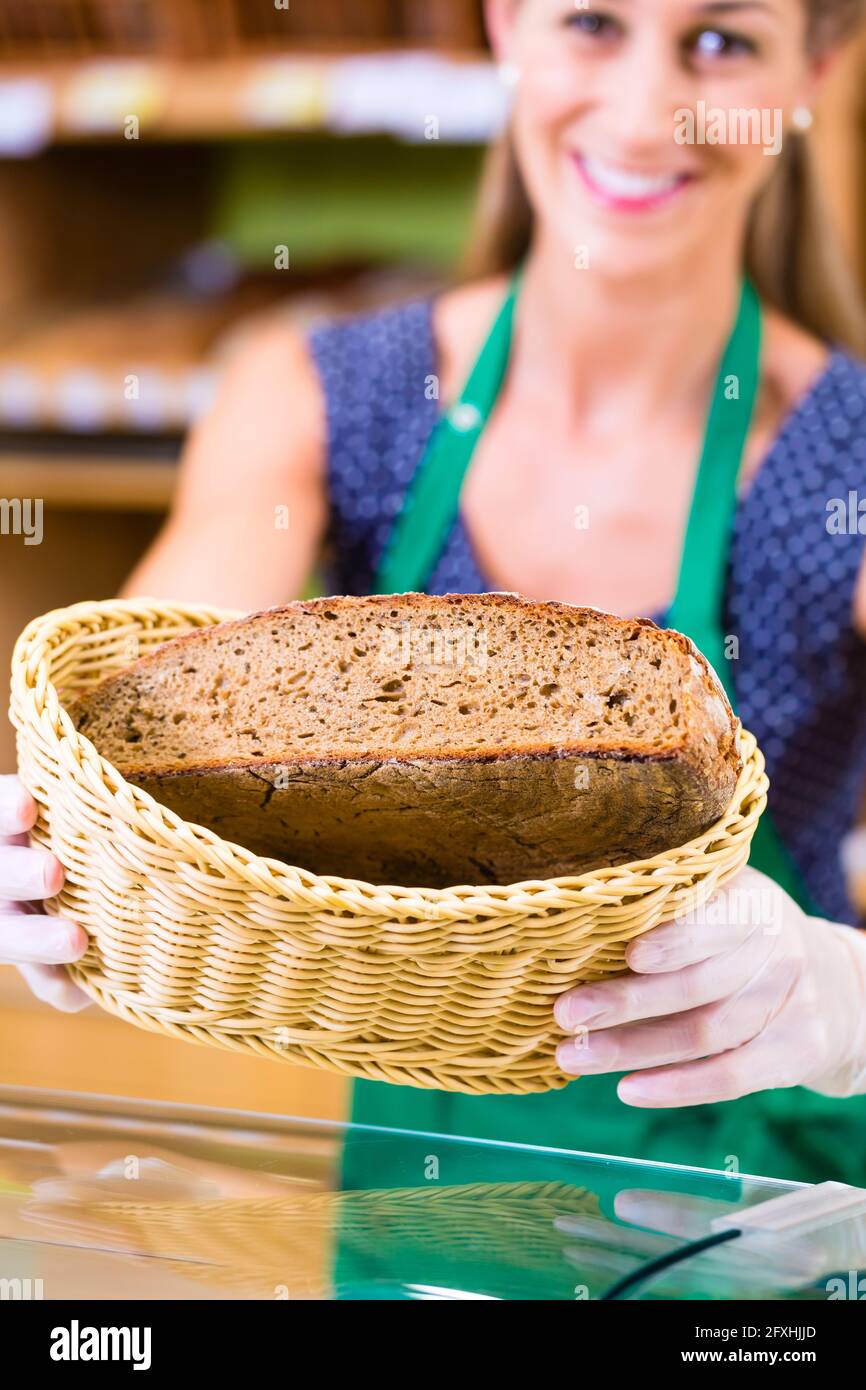 Female baker at organic supermarket bakery offering customer bread ...