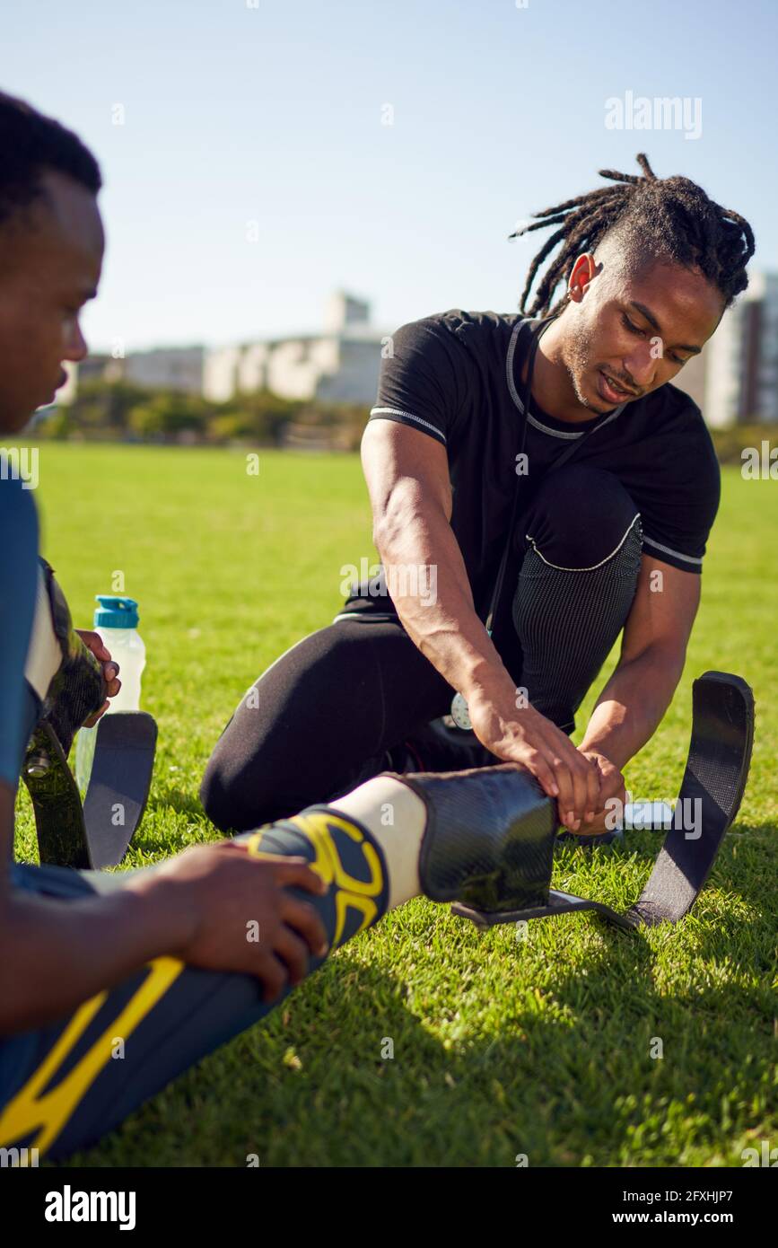 Coach helping young male amputee athlete with prosthetic in park Stock ...