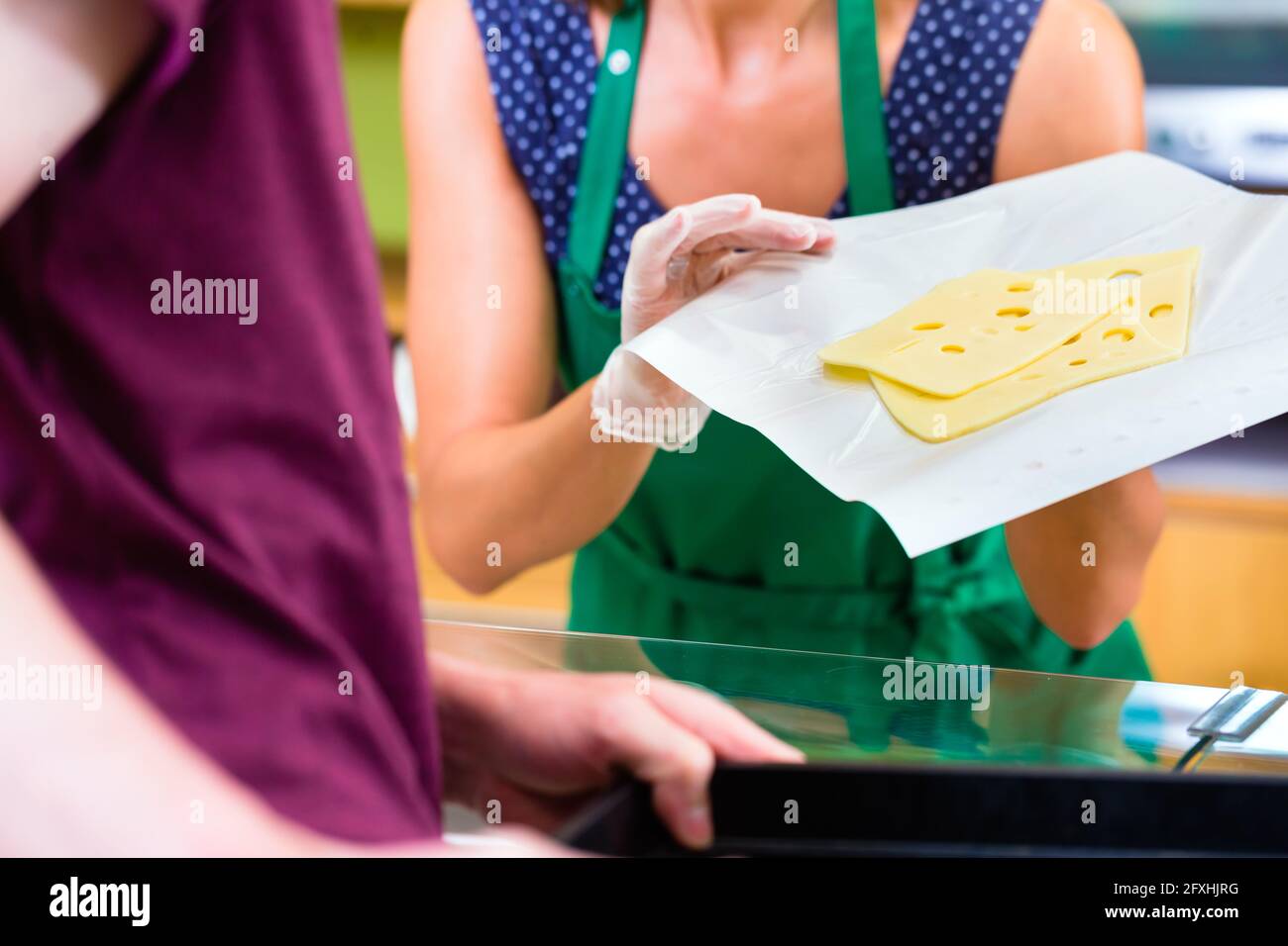 Saleswoman at organic supermarket counter offering customer cheese ...