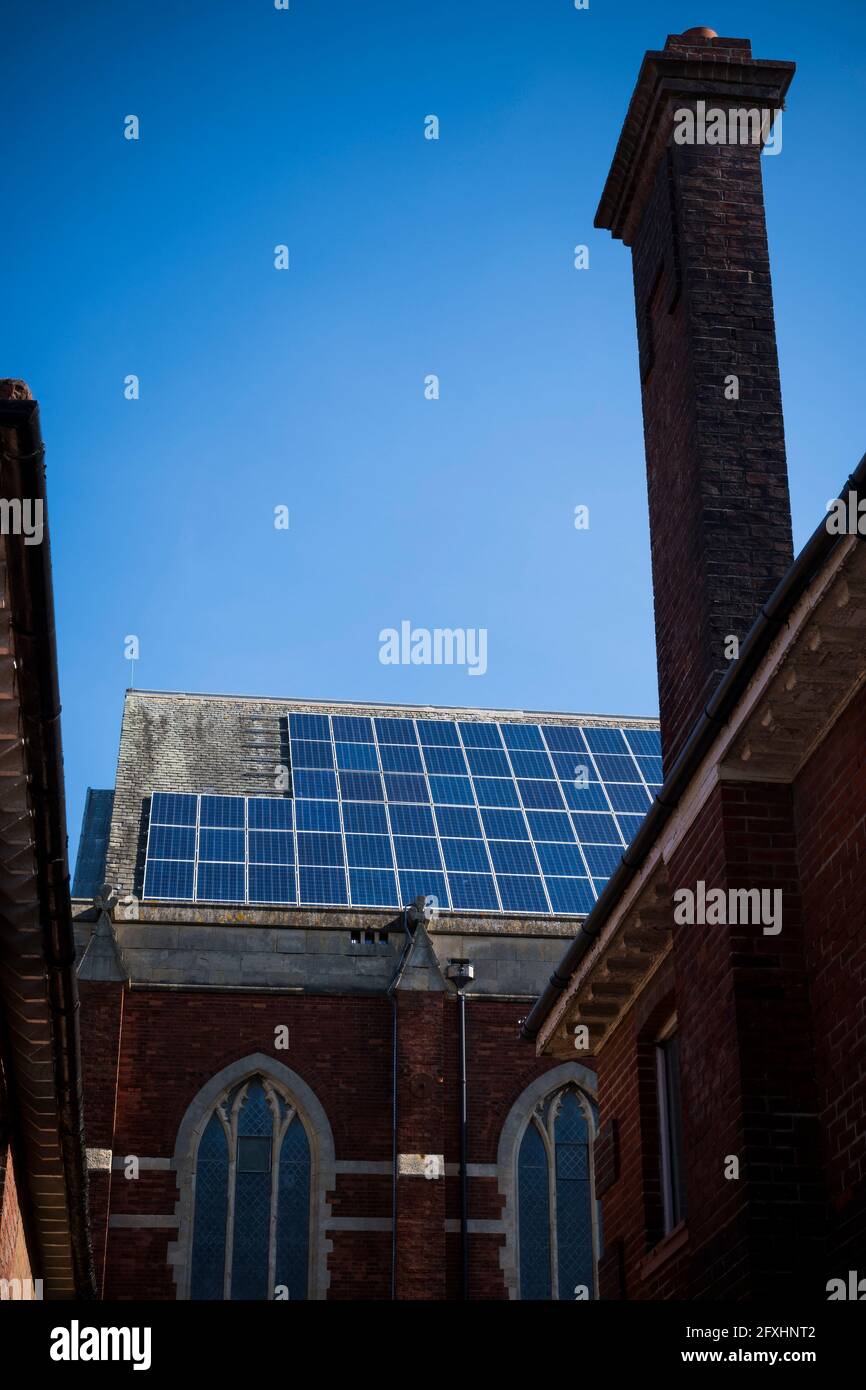 Looking up between buildings at church with solar panels Stock Photo ...