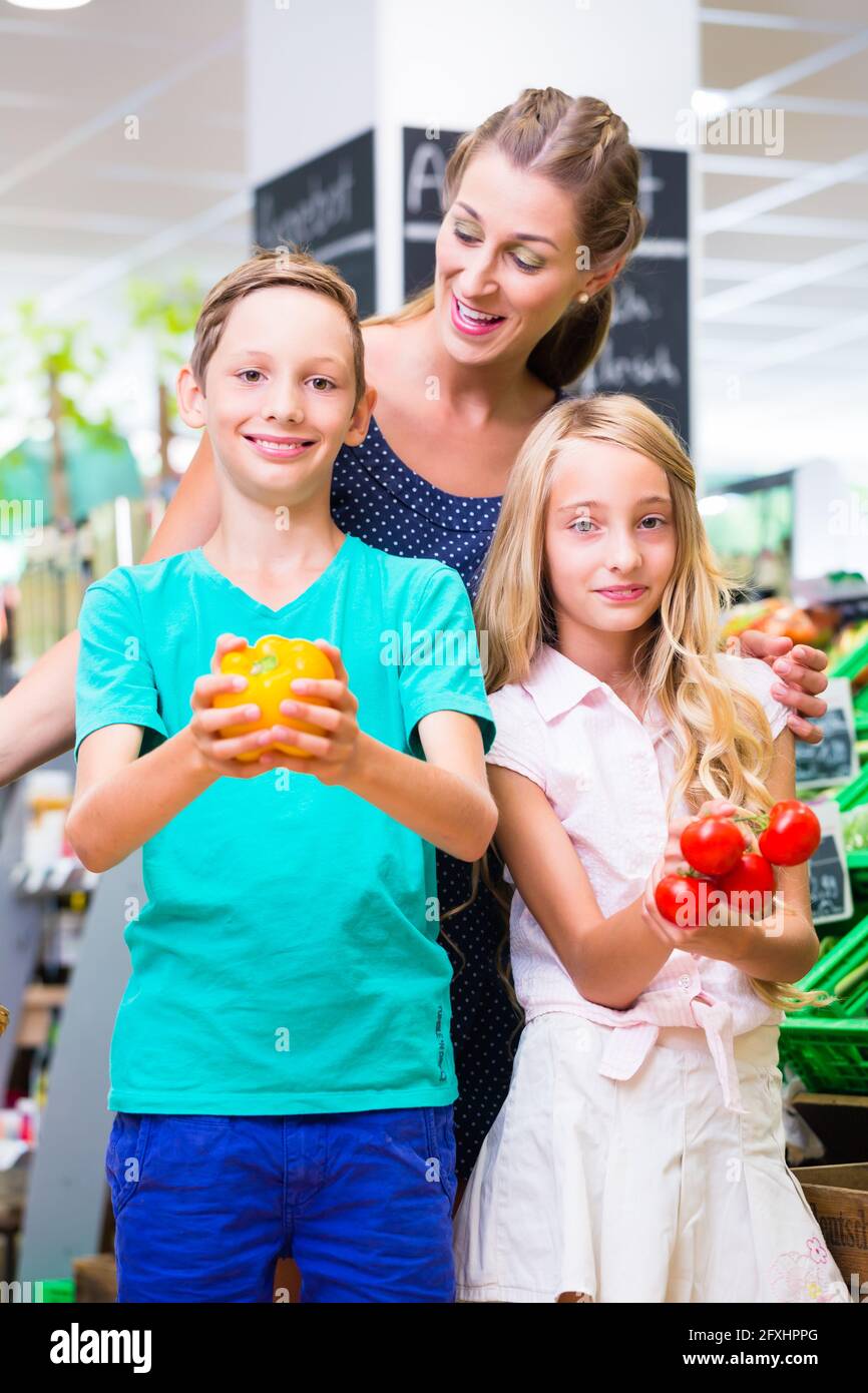 Mother and children selecting vegetables while grocery shopping in ...
