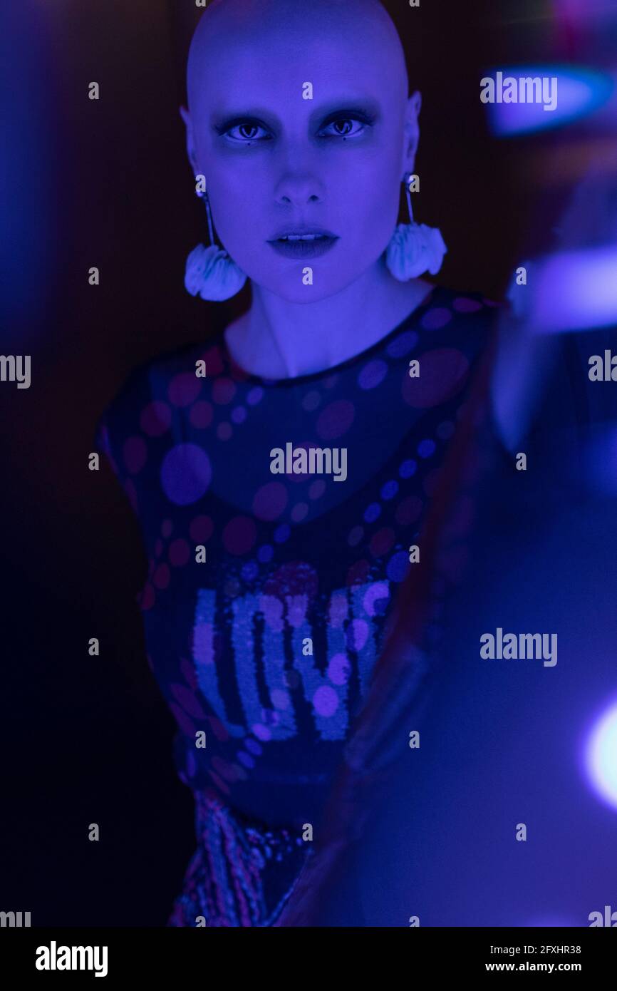 Portrait serious woman with shaved head in dark neon blue light Stock ...