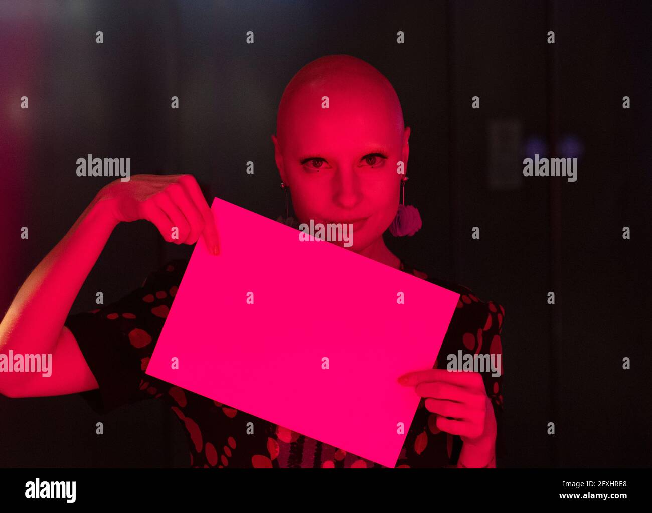 Portrait woman with shaved head holding blank sign in red light Stock ...