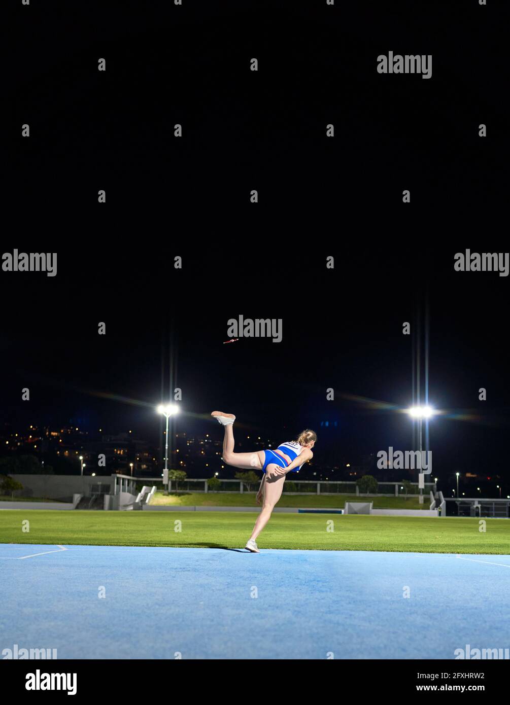 Female track and field athlete throwing discus at stadium at night ...