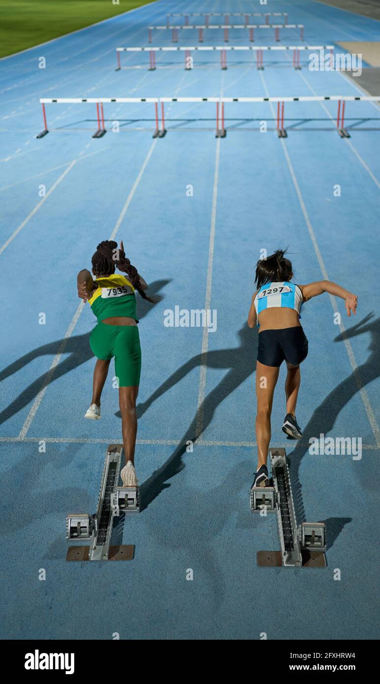 Female track and field athletes starting hurdle competition Stock Photo ...