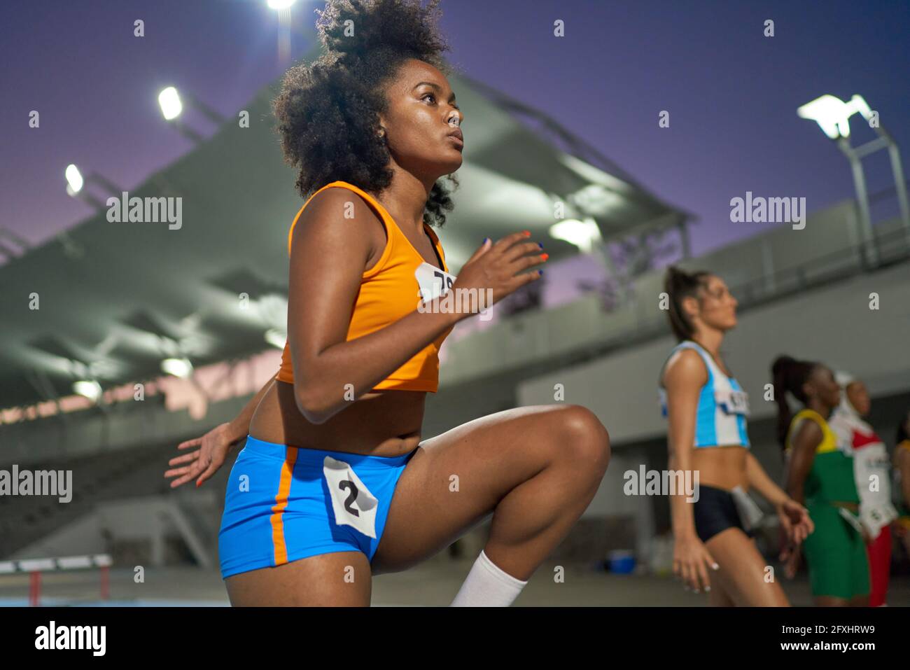 Focused female track and field athlete preparing for race in stadium ...