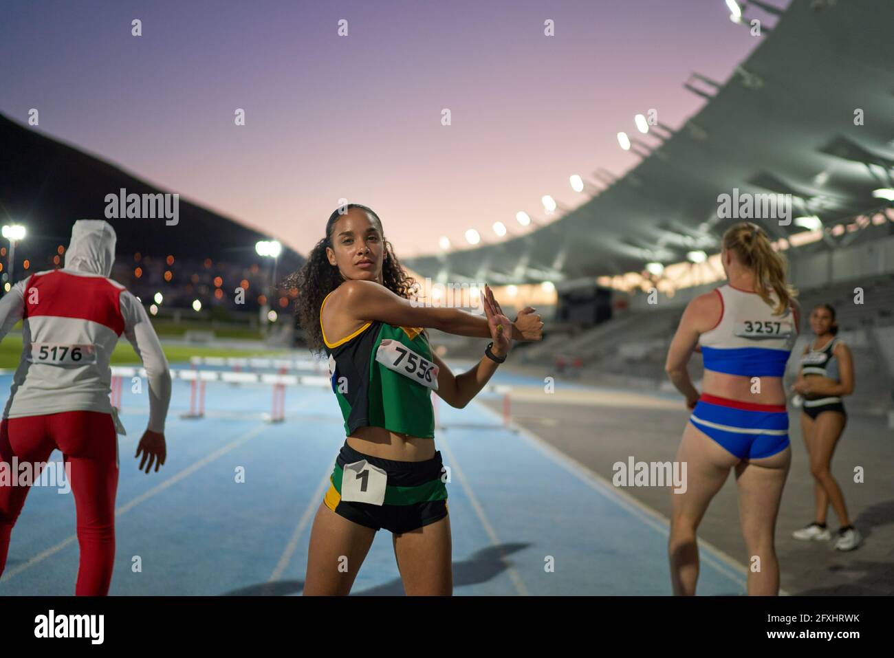 Portrait tough female track and field athlete stretching competition ...