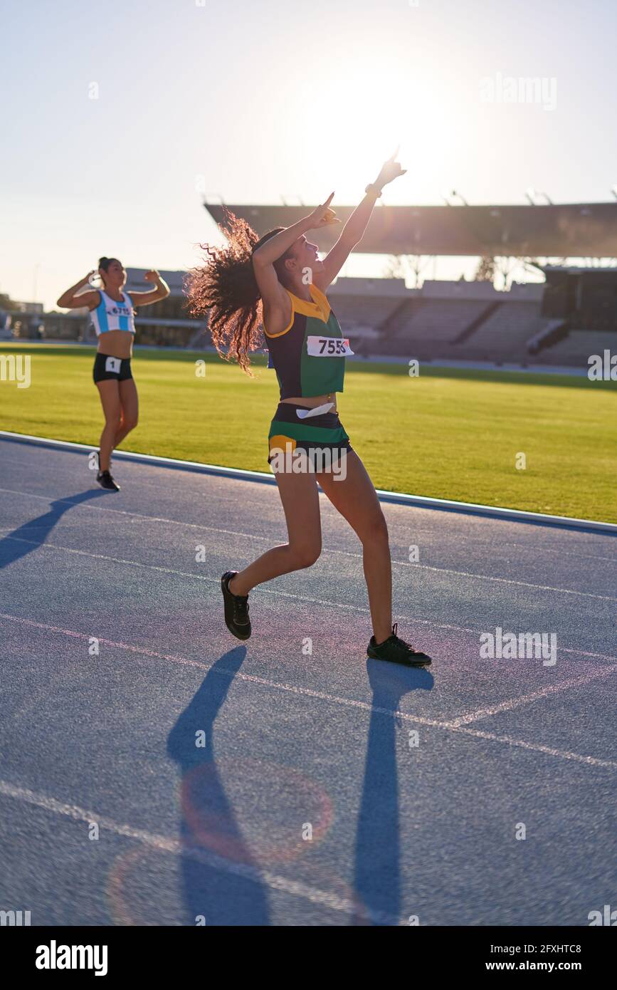 Female track and field athlete celebrating after race on sunny track ...