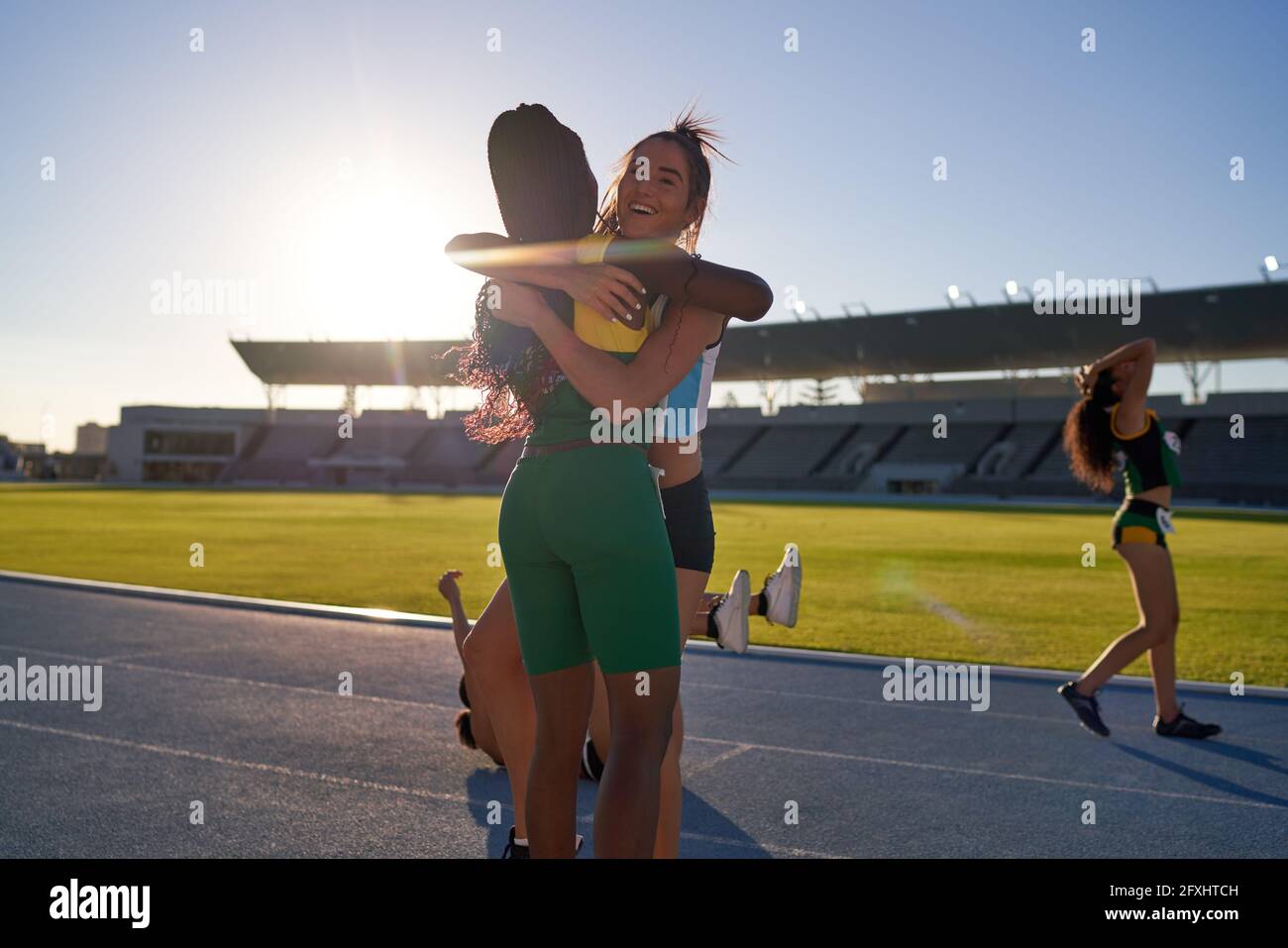 Happy female track and field athletes hugging on sunny track Stock ...