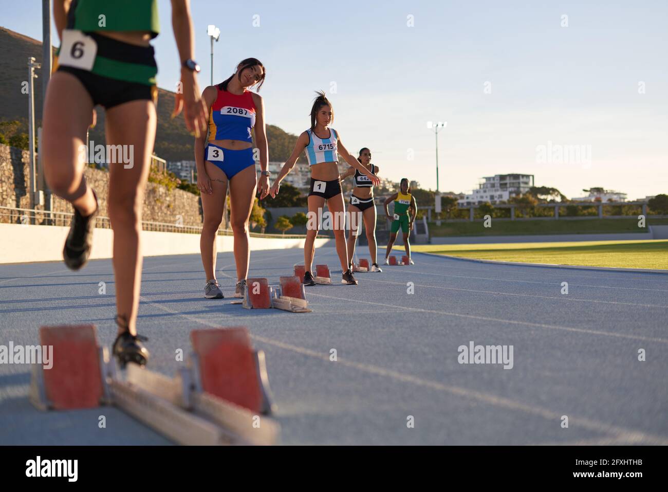 Female track and field athletes preparing at starting blocks on track ...