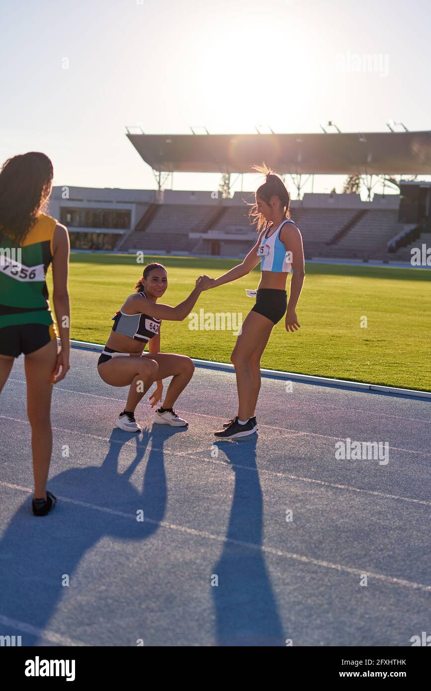 Female track and field athlete helping runner get up on track Stock ...