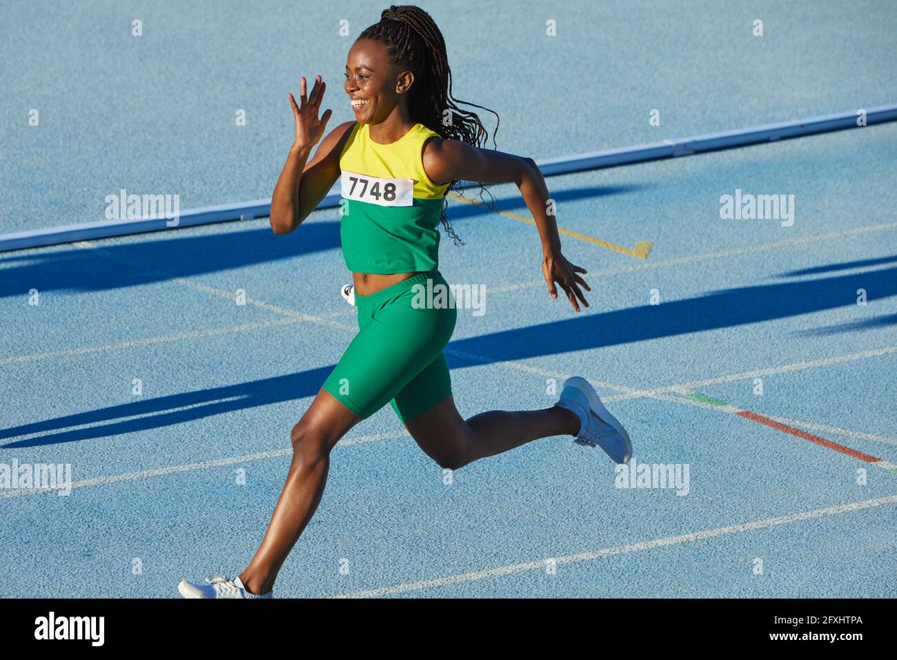 Smiling female track and field athlete running on sunny track Stock ...