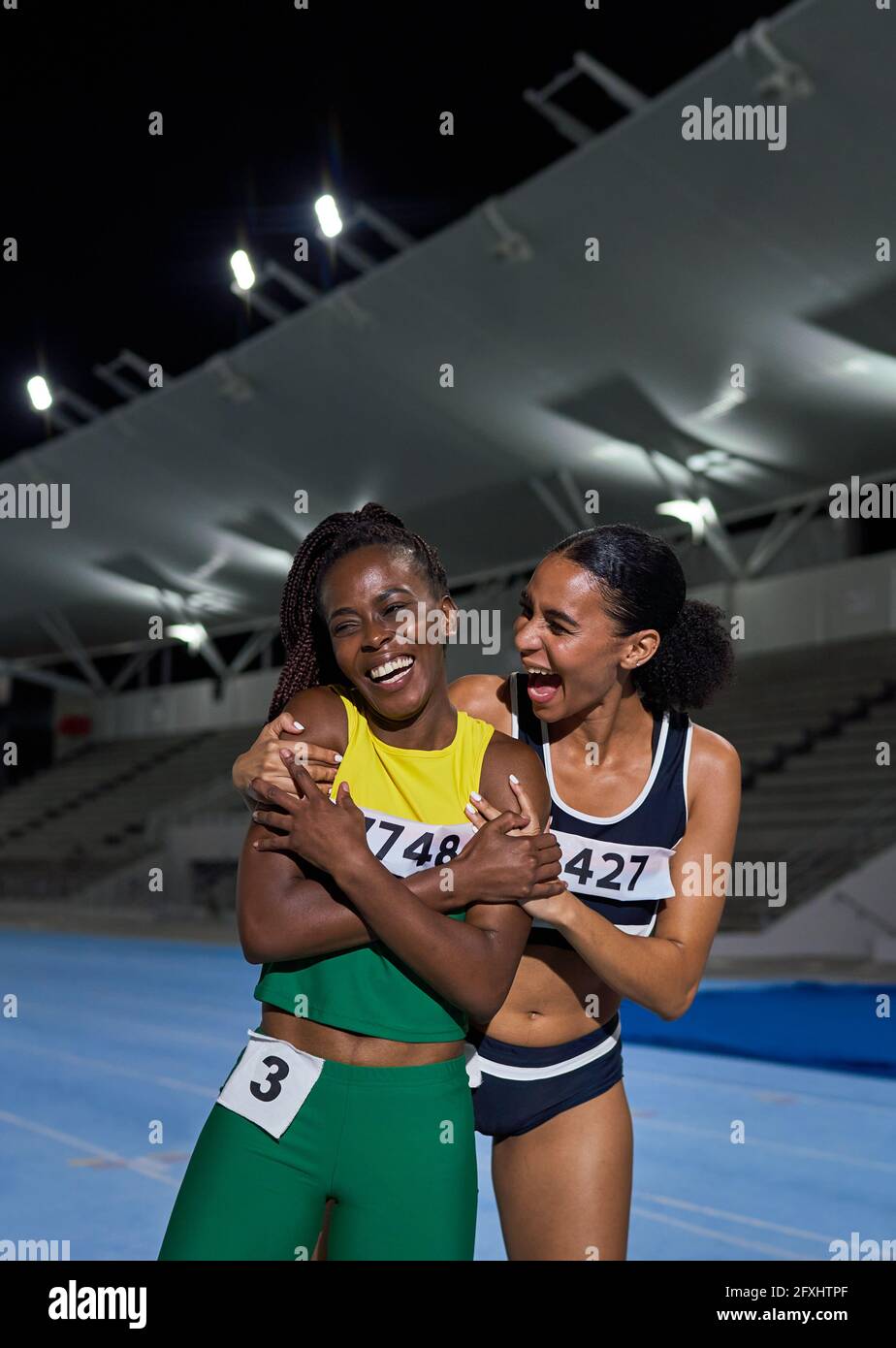 Happy female track and field athletes hugging after competition Stock ...