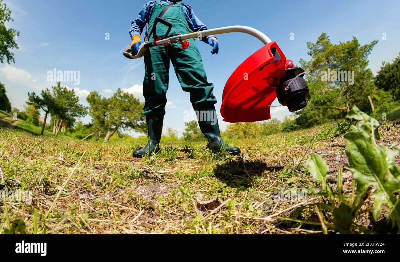 Photo of worker in green overalls and rubber boots using electric ...