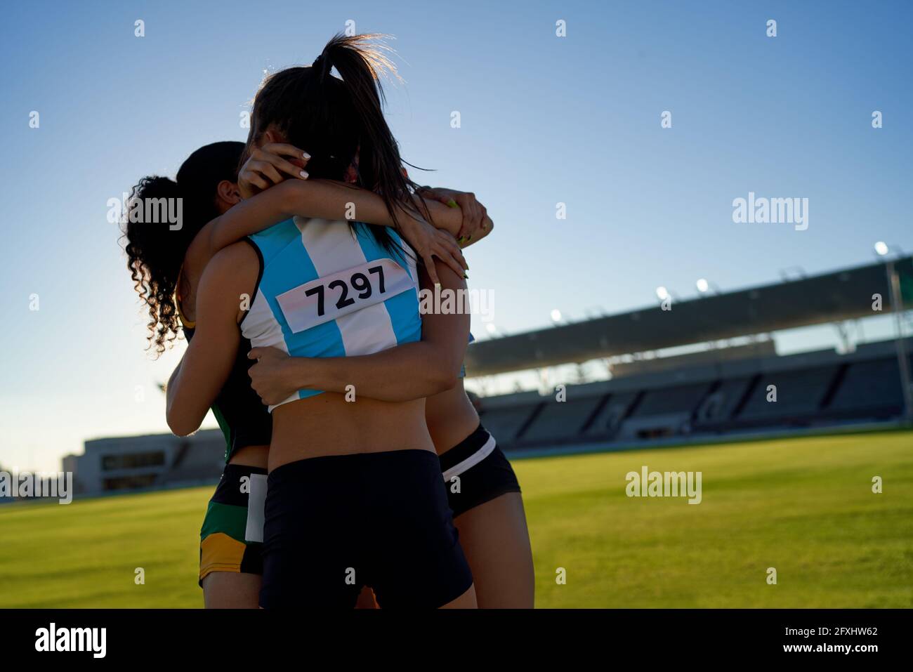 Happy female track and field athletes hugging in stadium infield Stock ...