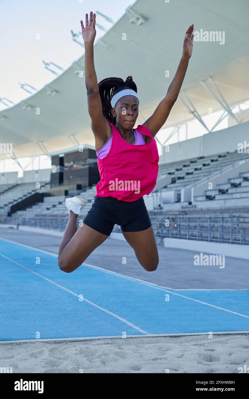Female track and field athlete long jumping over sand Stock Photo - Alamy