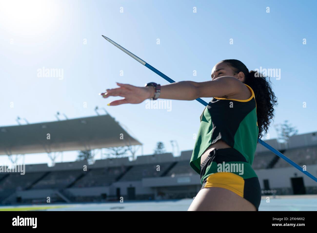 Focused female track and field athlete throwing javelin in stadium ...