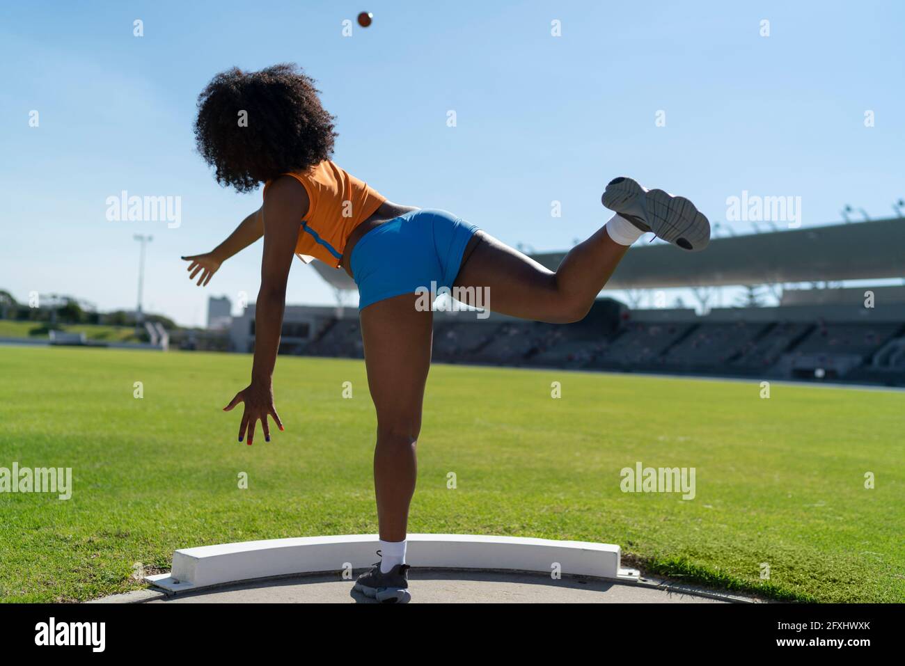 Female track and field athlete throwing shot put in sunny infield Stock ...