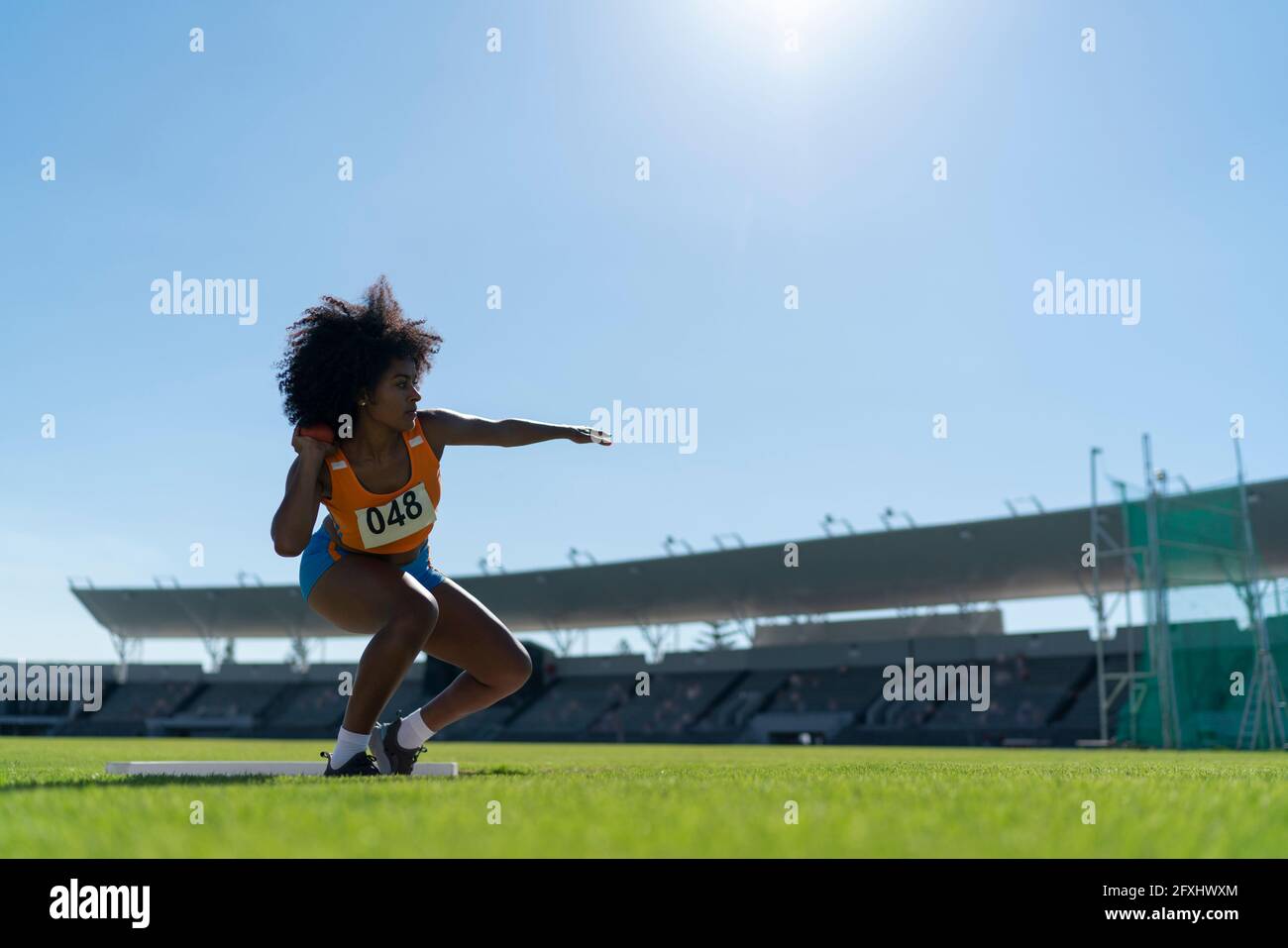 Female track and field athlete throwing shot put in sunny stadium Stock ...