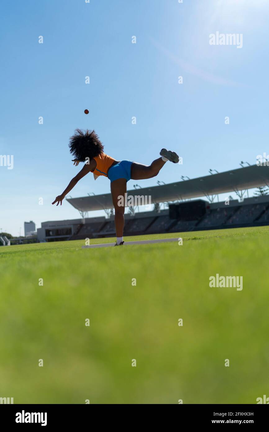 Female track and field athlete throwing shot put in sunny stadium Stock ...