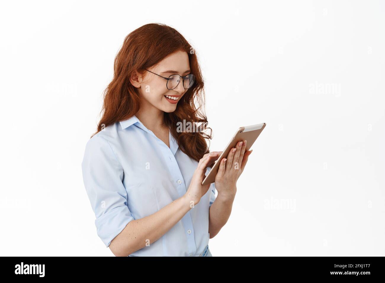 Female redhead office manager working on tablet, reading book on device ...