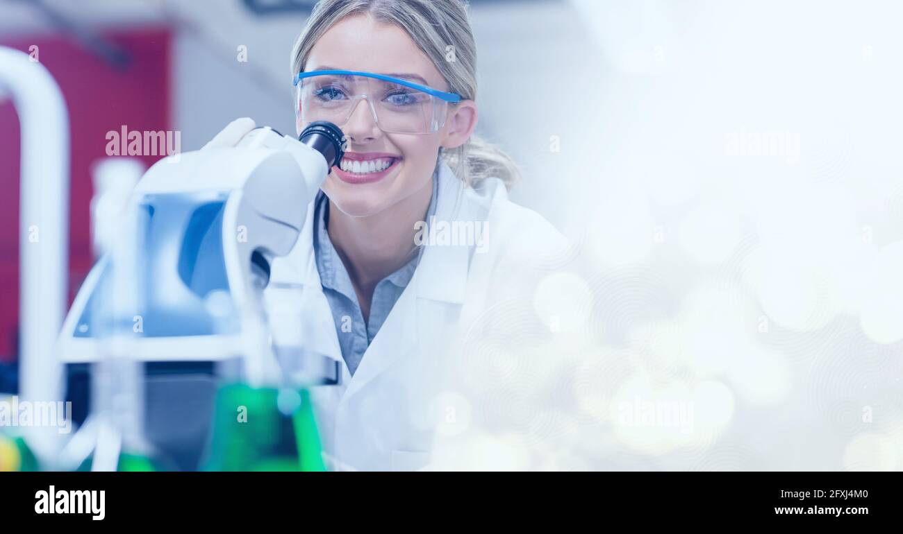 Composition of smiling female lab technicians using microscope, with ...