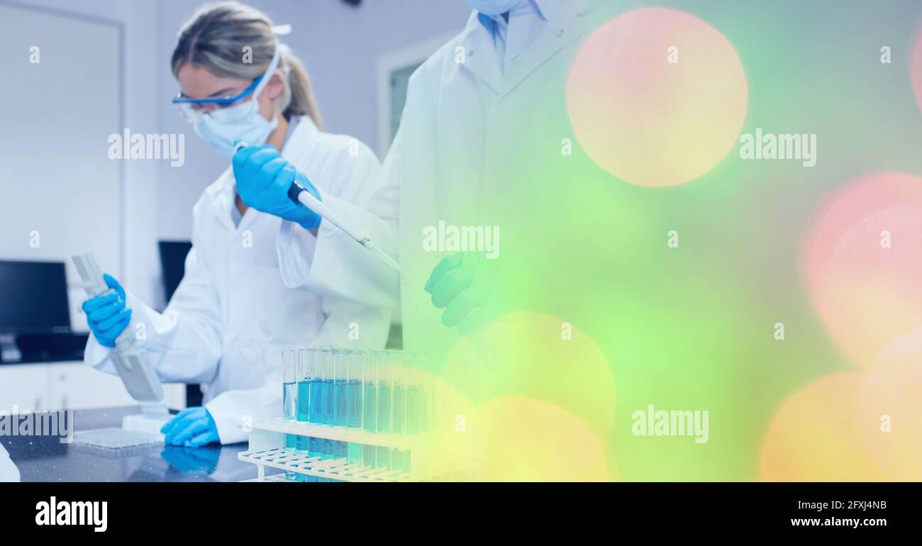 Composition of male and female lab technicians at work, with colourful bokeh copy space to right ...