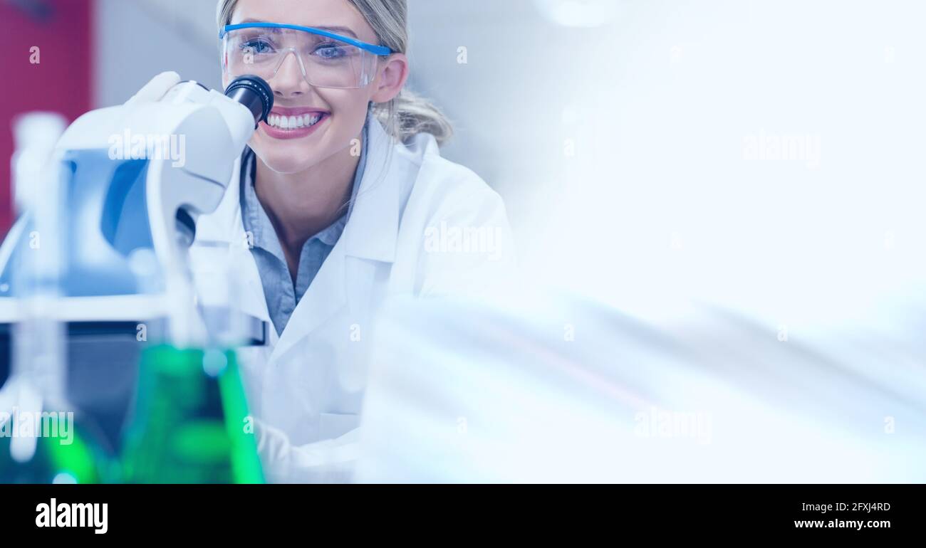 Composition of smiling female lab technician using microscope, with ...
