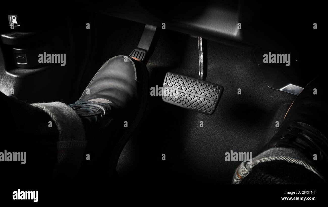 Foot pressing foot pedal of a car to drive. Accelerator and brake pedal ...