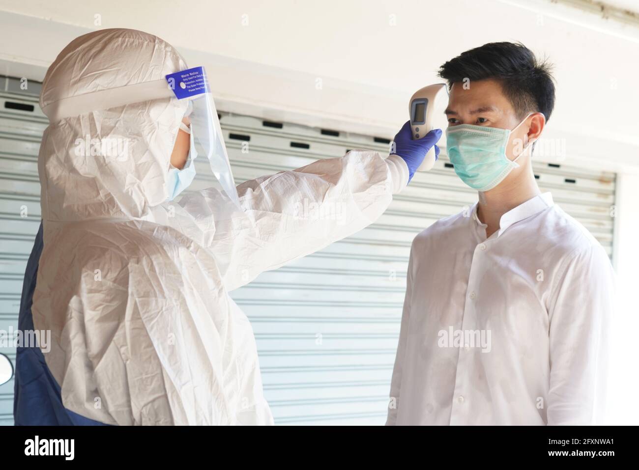 Disease control experts use an Infrared thermometer equipment to check ...