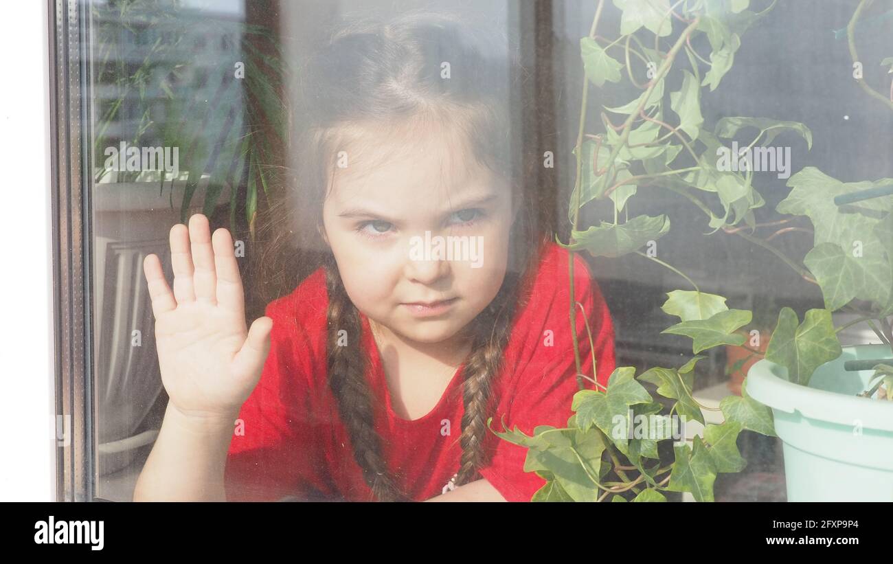 Beautiful little girl smiling and watching out the window. A child ...