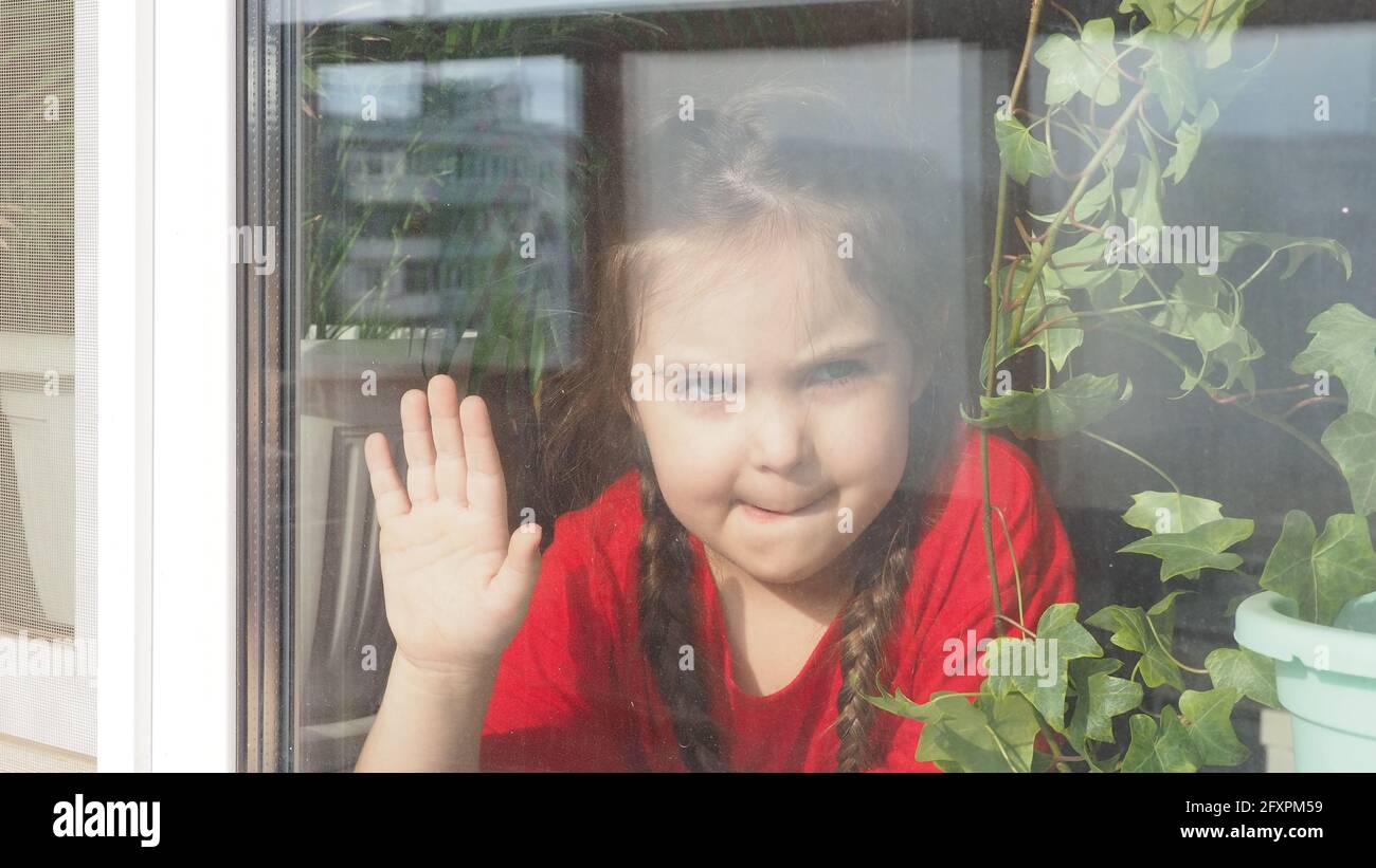 Beautiful little girl smiling and watching out the window. A child ...