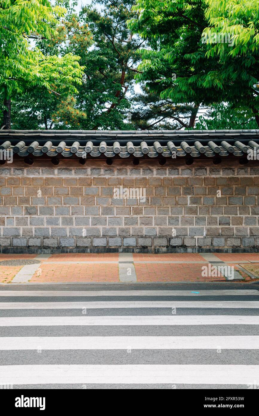 Korean traditional stone wall and crosswalk with green trees at Royal ...