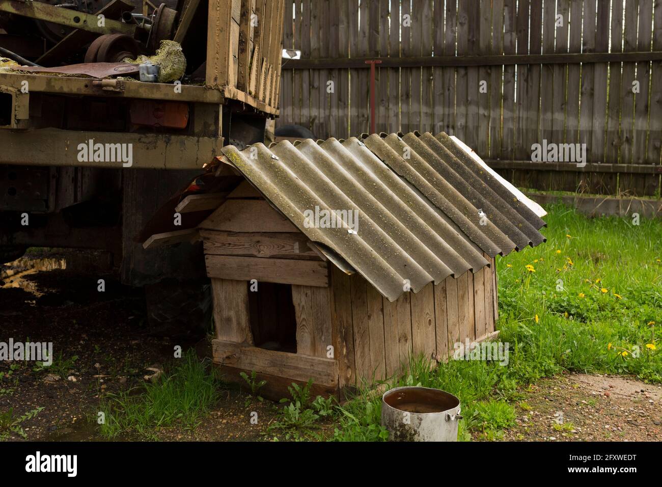 Wooden old doghouse in the grass near the house.one old empty wooden ...