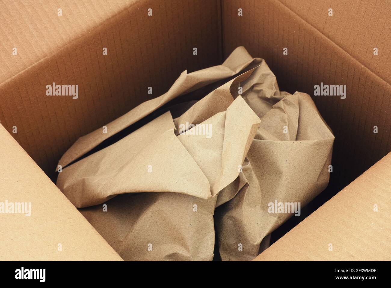 An open cardboard box with crumpled paper inside. Close up Stock Photo ...