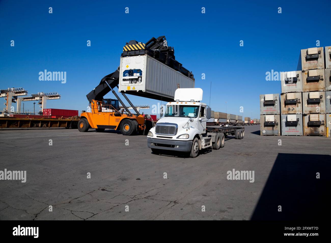 Mobile crane lifting up container in railroad yard and placing on ...