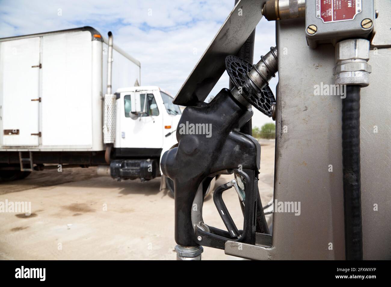 Diesel truck refueling station with nozzle in forground and truck in ...