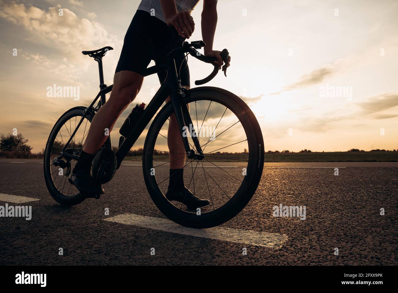 Close up of sporty young man standing on road with bike Stock Photo - Alamy