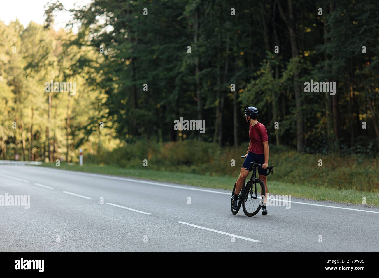 Professional cyclist standing on paved road with bike Stock Photo - Alamy