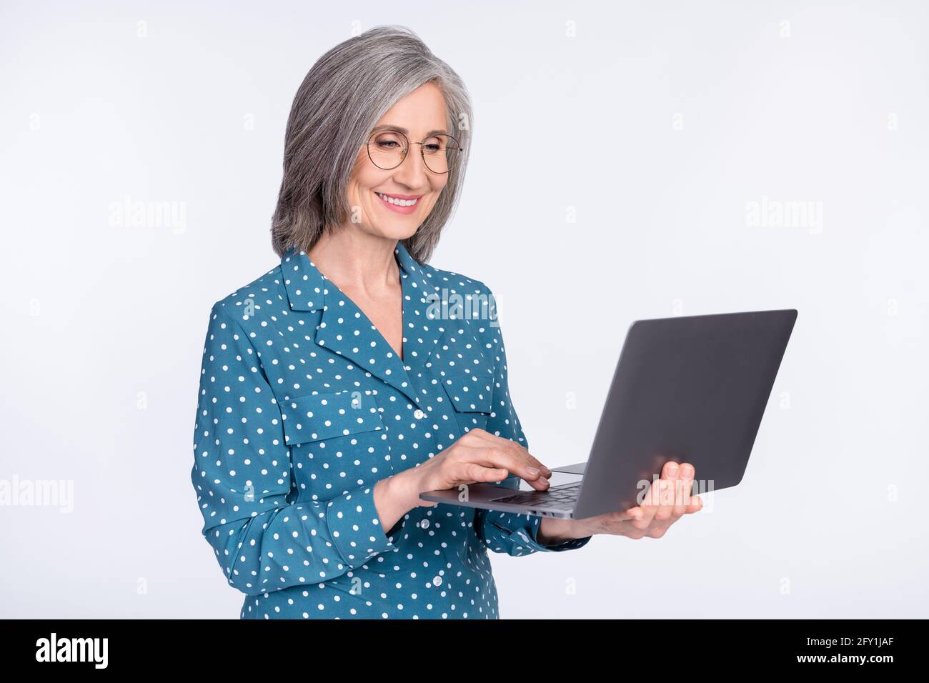 Photo of happy cheerful old woman hold computer work smile wear glasses ...