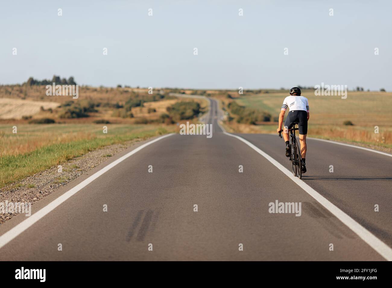 Sporty man cycling on white separation line of road Stock Photo - Alamy