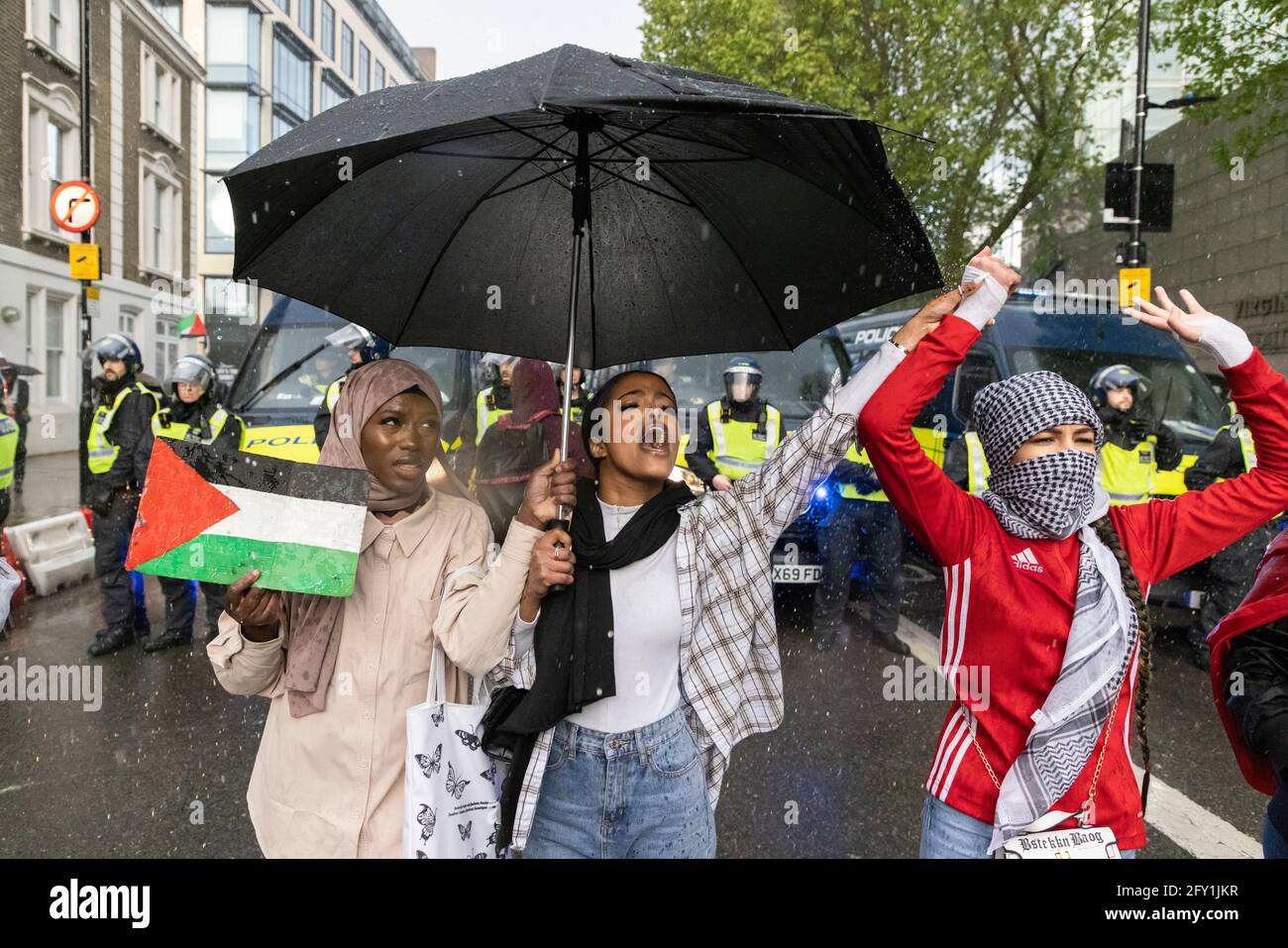 Protesters shouting in the rain while contained within police cordon ...