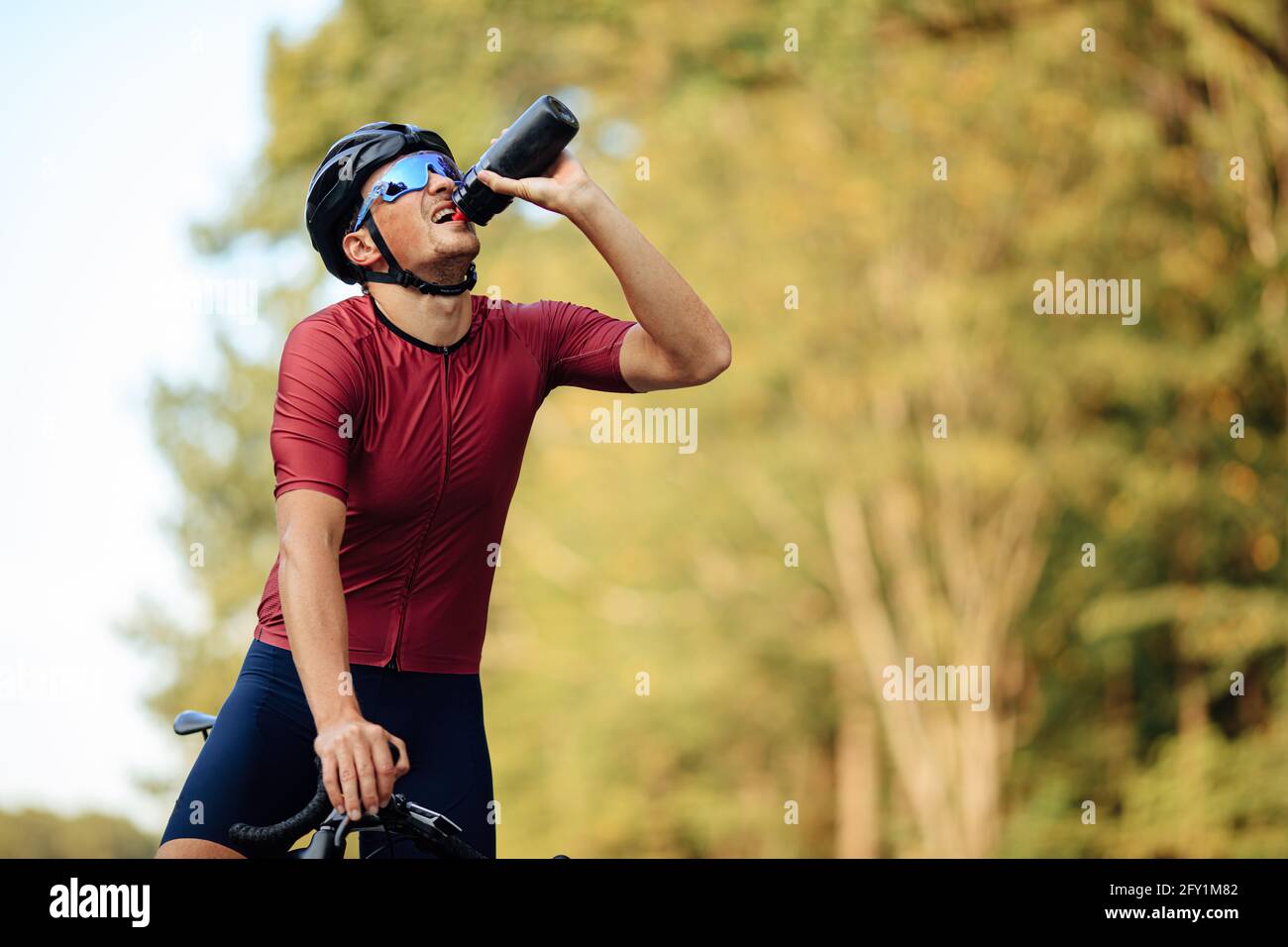 Exhausted road cyclist drinking water from bottle Stock Photo - Alamy